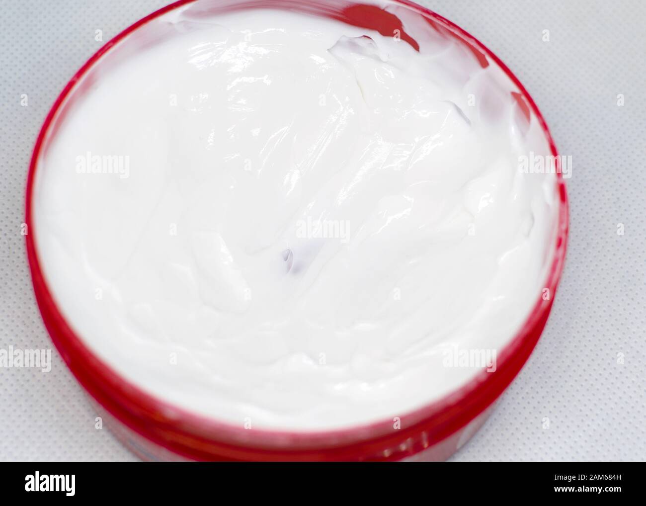 White cream in red can top view. Body care, cosmetology. thick cream ...