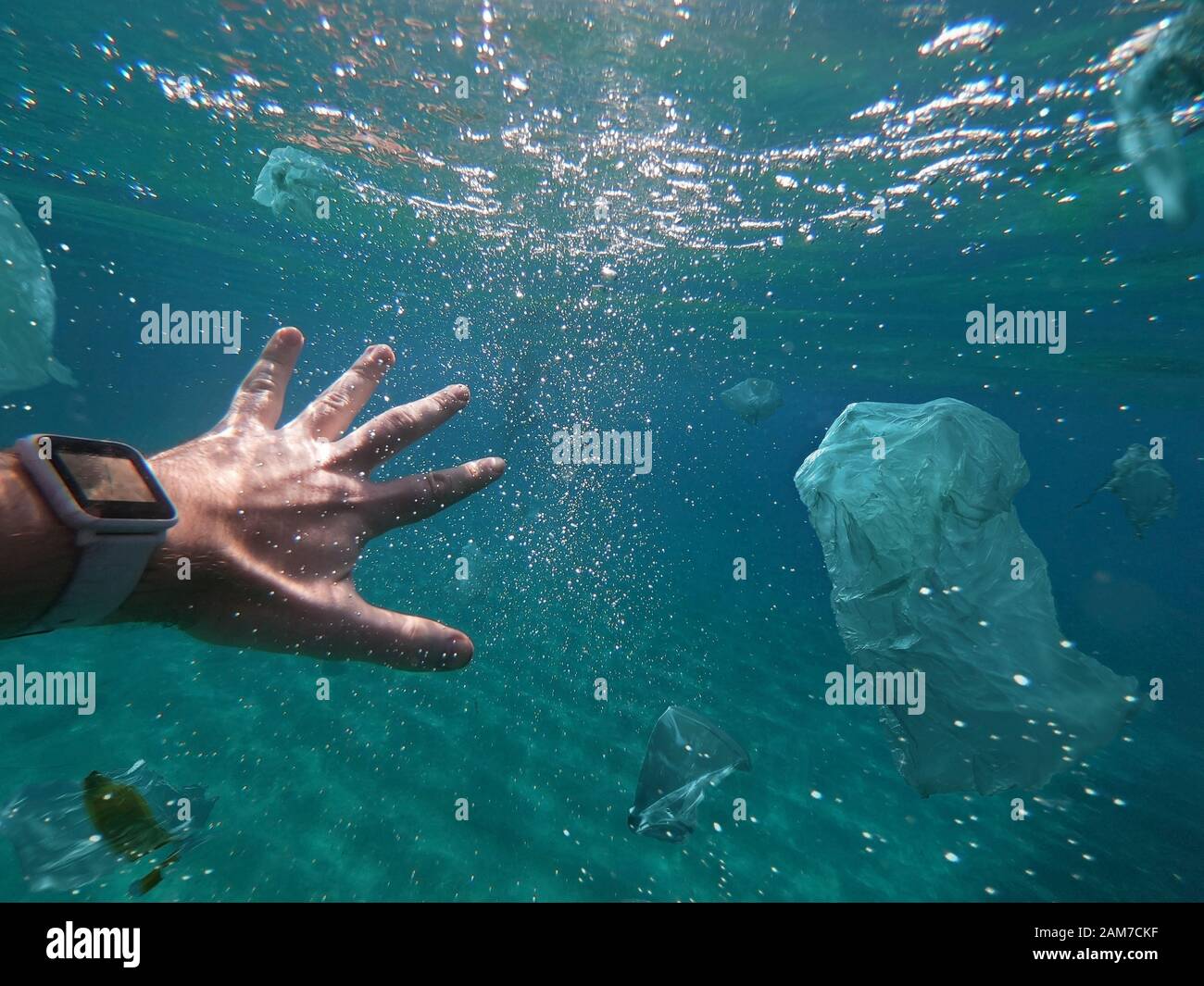 A man swimming among toxic plastic wastes floating in the ocean Stock ...