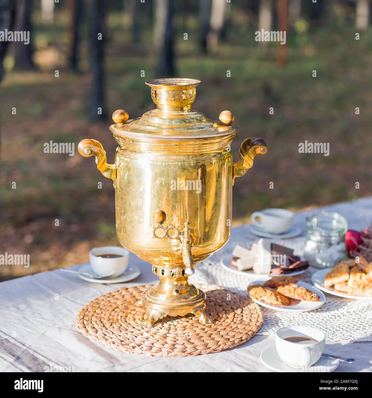 Golden russian samovar with tea cups and sweet snacks on table outdoor ...
