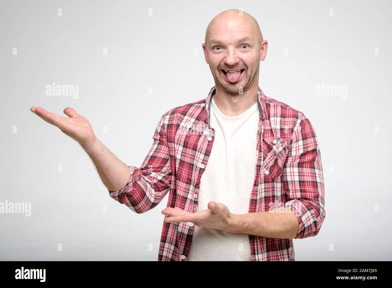 Bald man with a silly expression on face shows a gesture with hands to ...