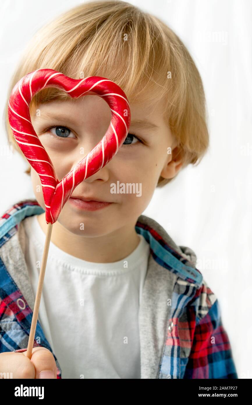 Cute little boy in with candy red lollipops in heart shape, white ...