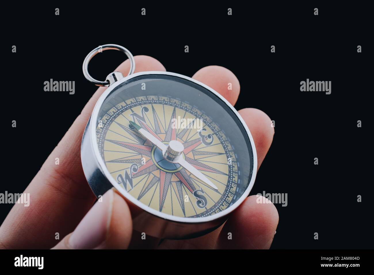 Hand is holding a magnetic compass on black background Stock Photo - Alamy