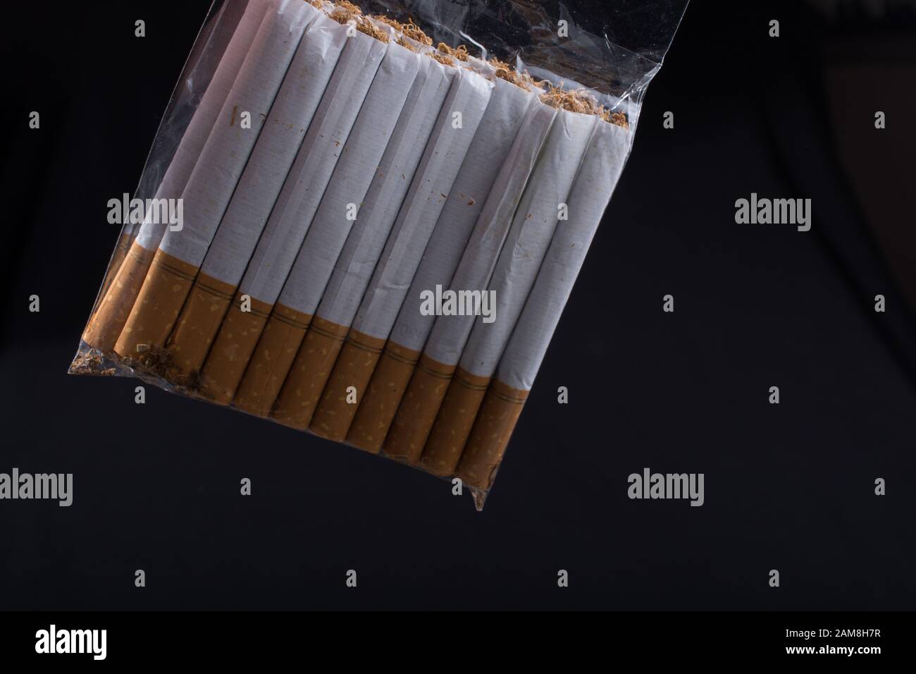 Pack of cigarette hanging on black background Stock Photo - Alamy