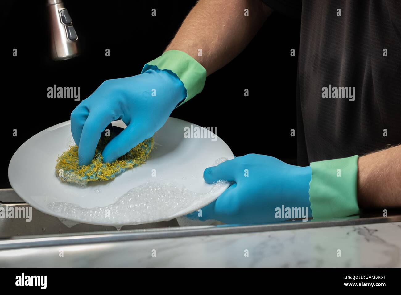 Close up of a model's hands washing dishes with light blue rubber ...