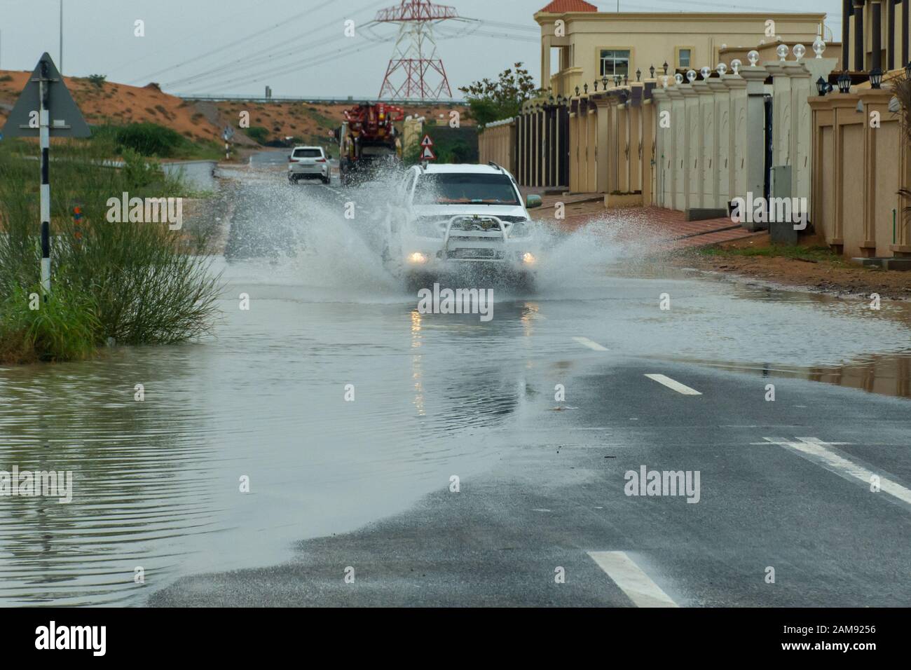 Truck driving through flood waters on the street making large splashes ...