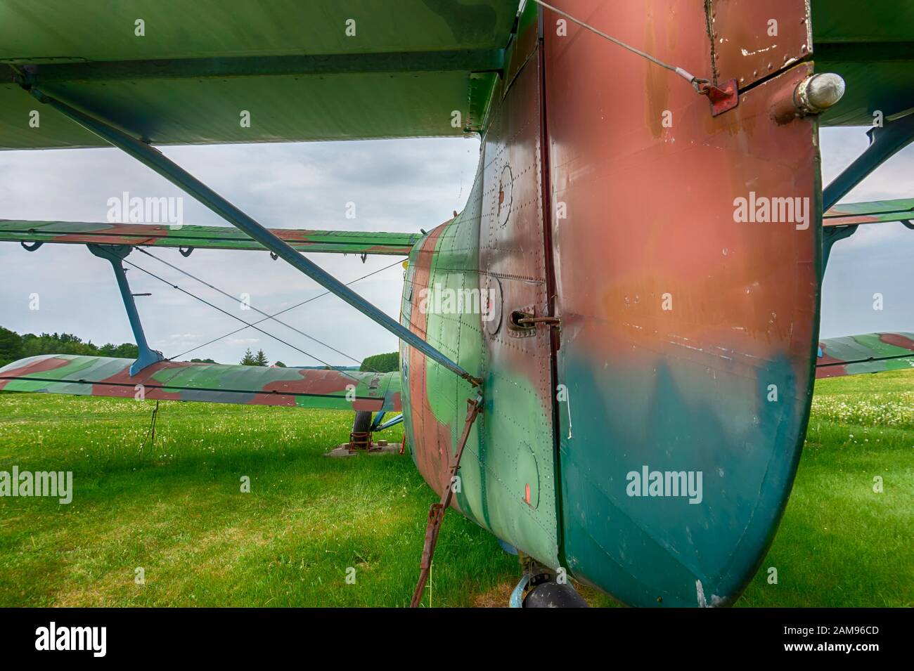 Vintage green biplane parked on exhibit in a lush green field viewed ...