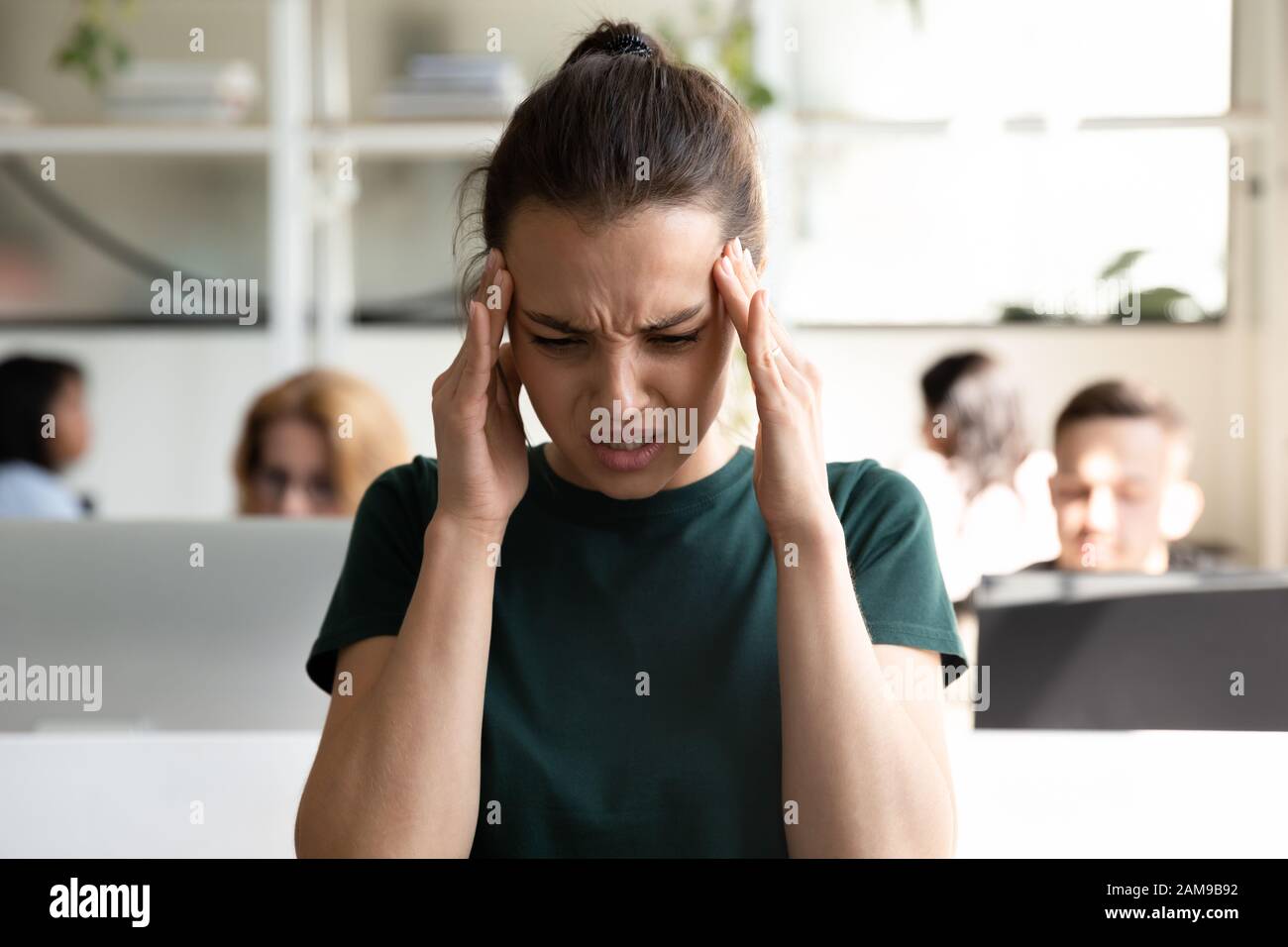 Female office worker suffers from sudden throbbing headache Stock Photo ...