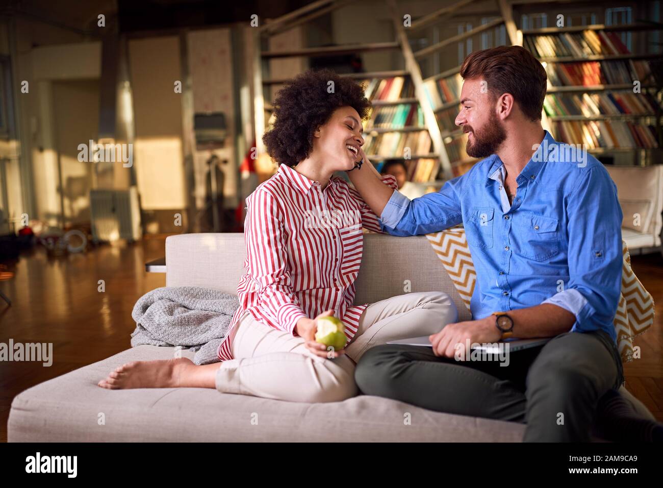 Man cuddling young woman at sofa in room Stock Photo - Alamy