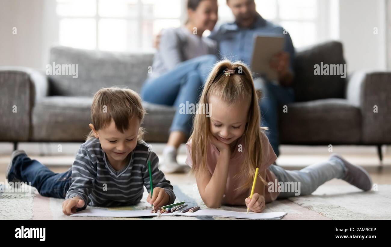 Happy small siblings lying on floor painting picture together Stock ...