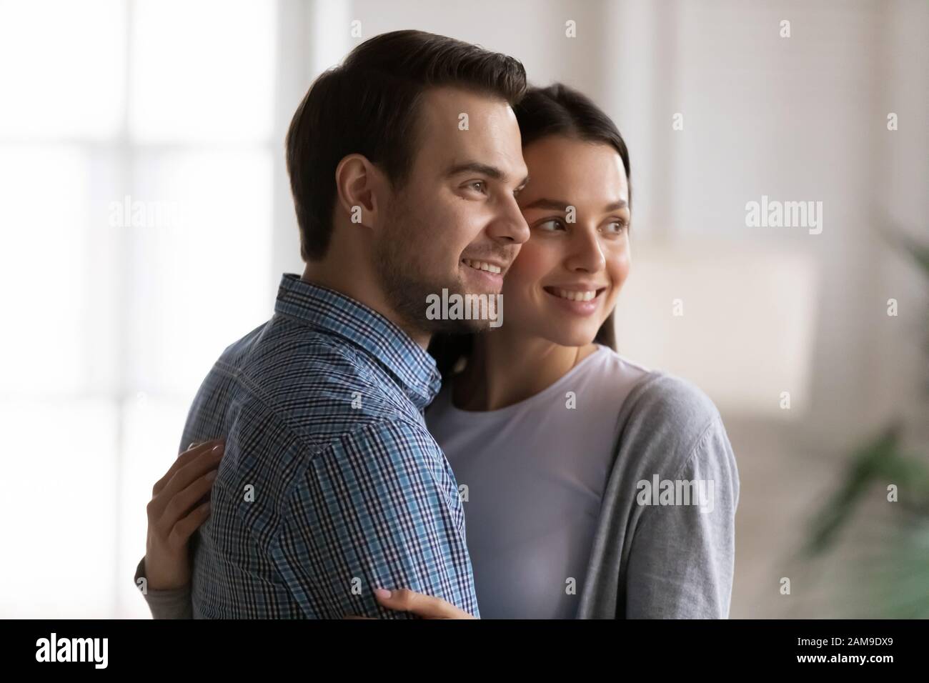 Happy young couple hug look in distance dreaming Stock Photo - Alamy