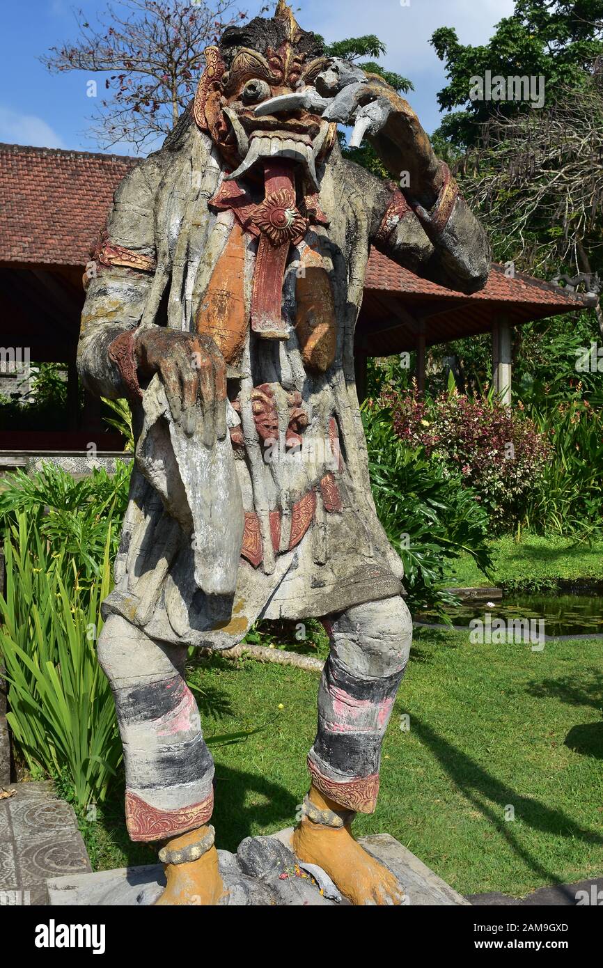 Standing demon stone statue with weathered surface paint on premises of ...