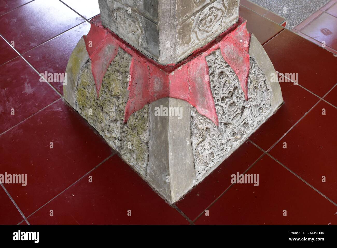 Stone pillar foot with carved relief on smooth red tile floor Stock ...