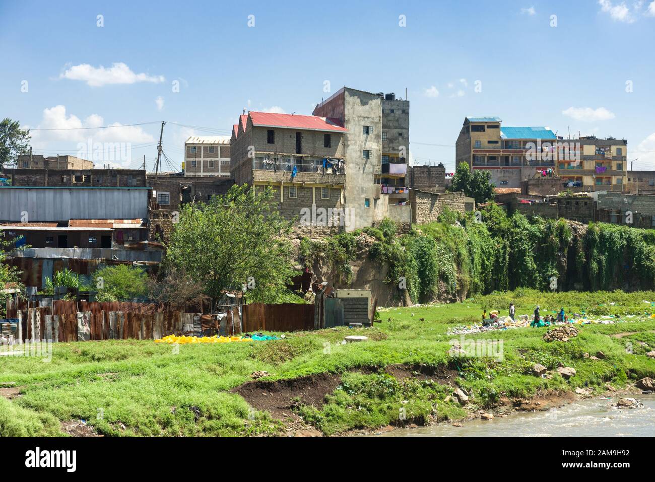 Buildings and shacks by Nairobi river as locals work sorting rubbish ...