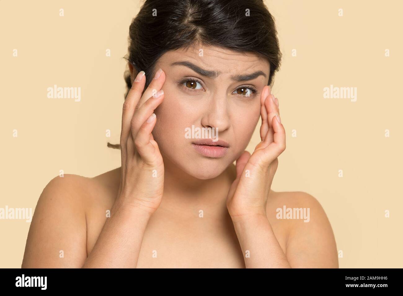 Frowning young indian ethnicity woman examining wrinkles Stock Photo ...