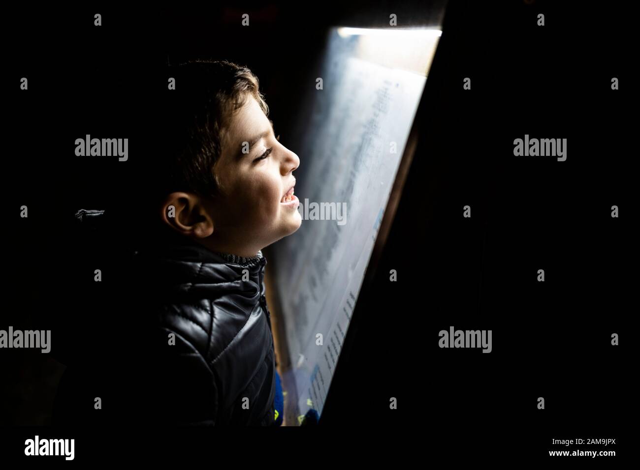 Little boy reading a poster at night Stock Photo - Alamy