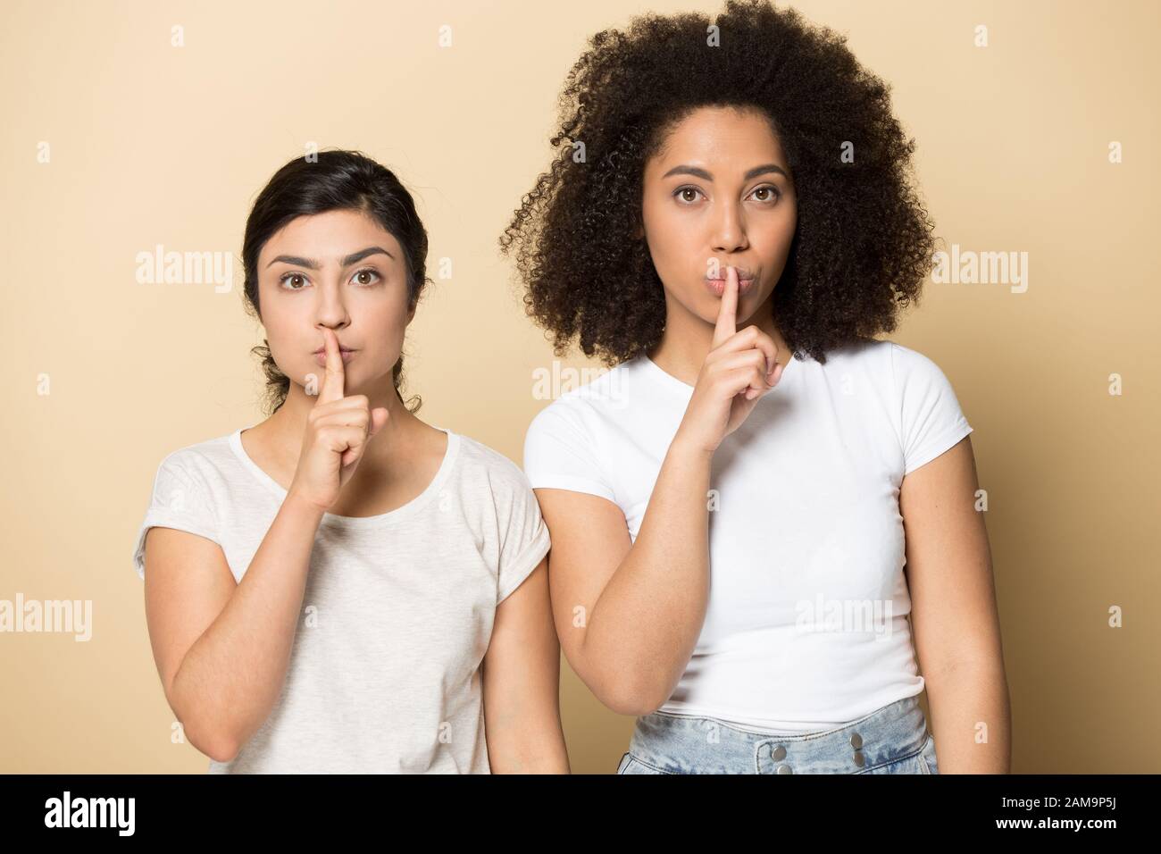 Mysterious multiracial female friends making hush gesture Stock Photo ...