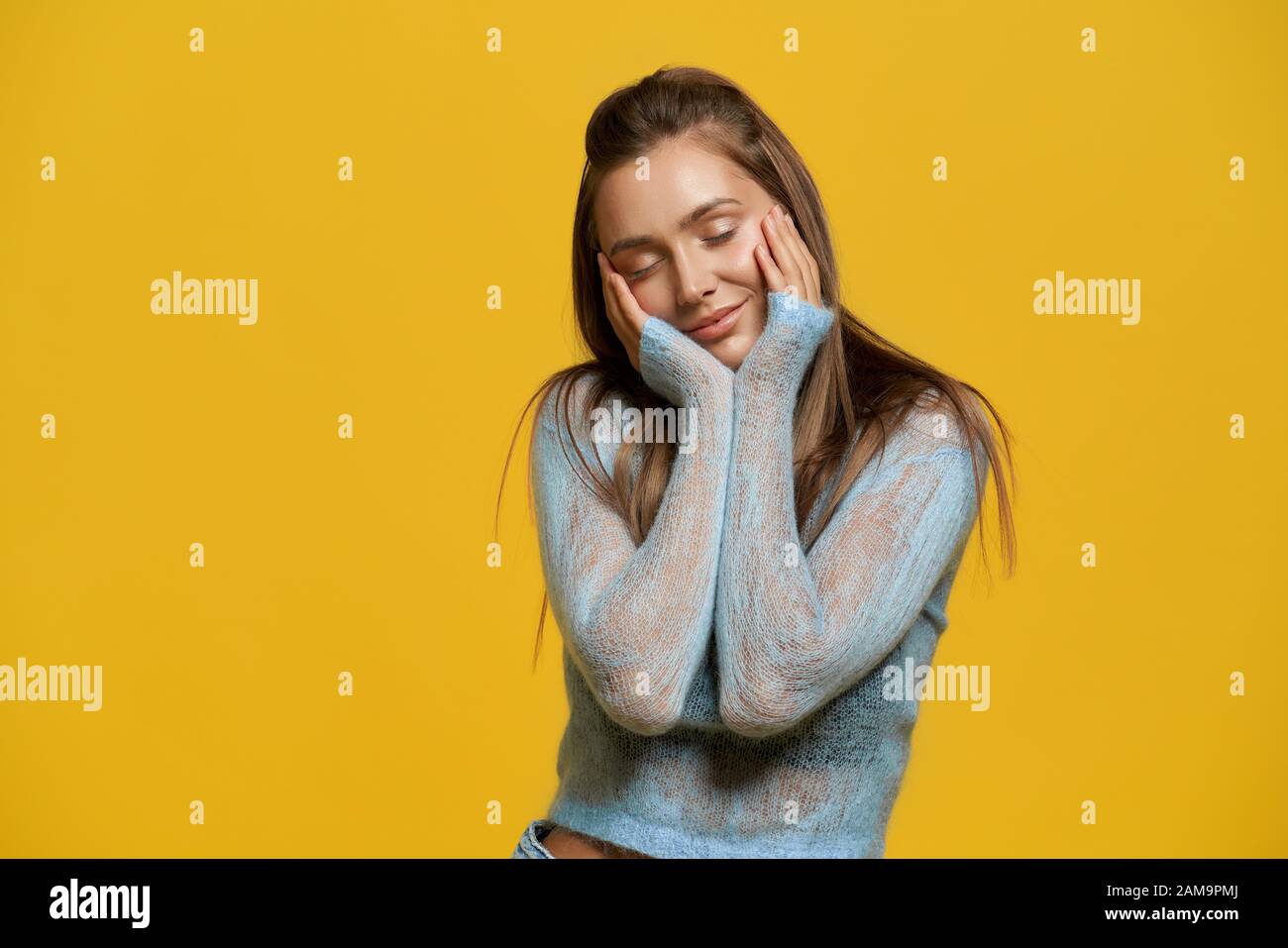 Attractive calm smiling girl with long brown hair touching cheeks with ...