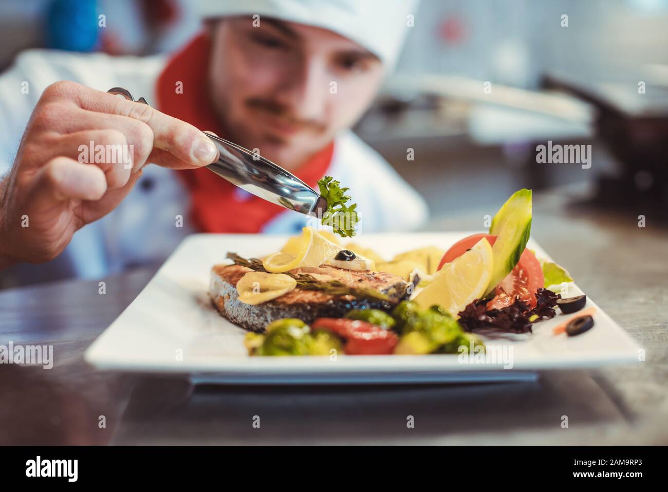 Proud chef garnishing an almost finished dish in the restaurant with ...