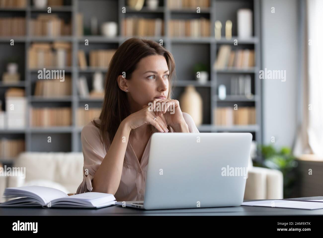 Pensive young woman distracted from work thinking Stock Photo - Alamy