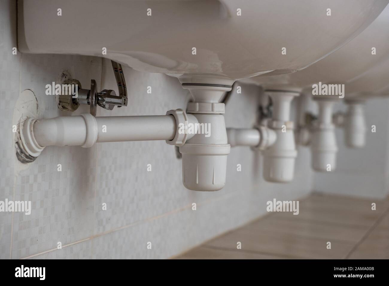 Close up of white plastic pipe drain under washing sink in bathroom ...