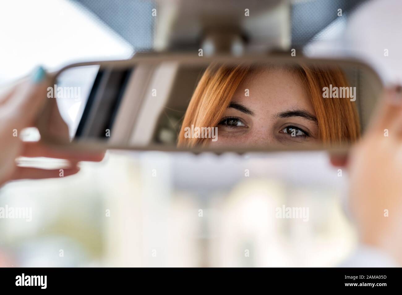 Young woman driver checking rear view mirror looking backwards while ...