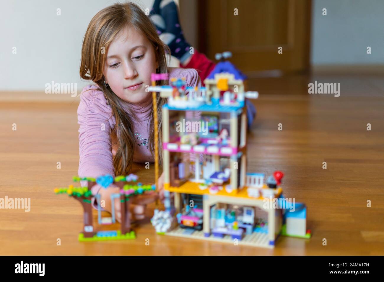 Little girl plays with a children's constructor at home. Little girl ...