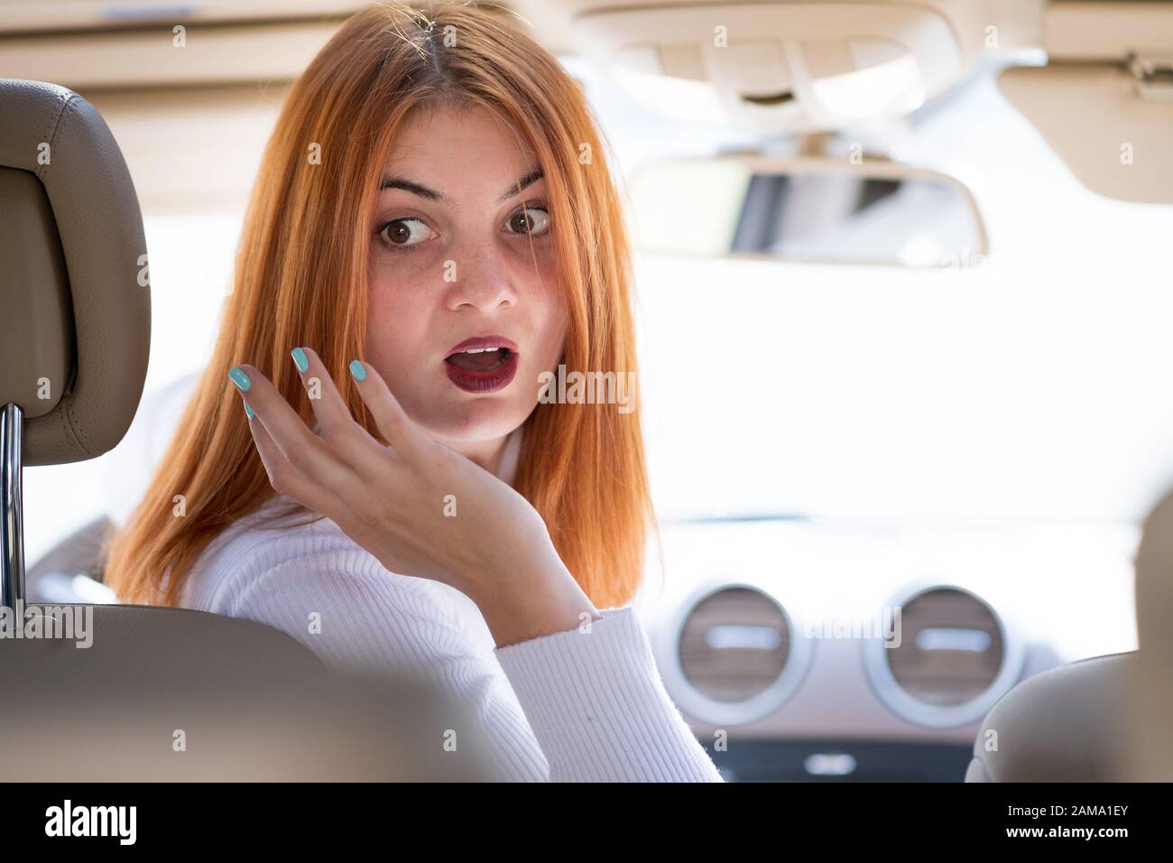 Young woman driving a car backwards. Girl with funny expression on her ...