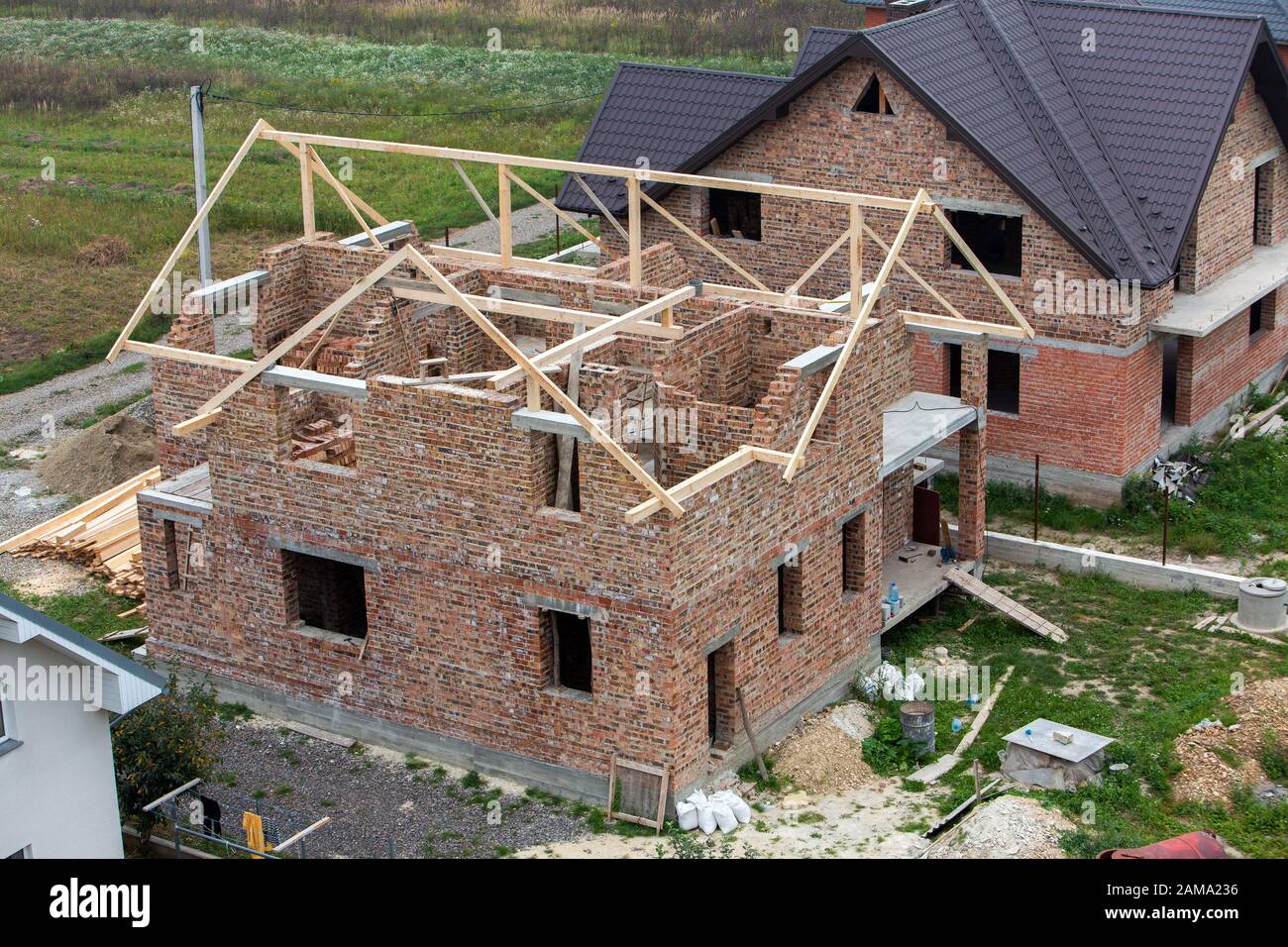 Unfinished brick house with wooden roof structure under construction ...