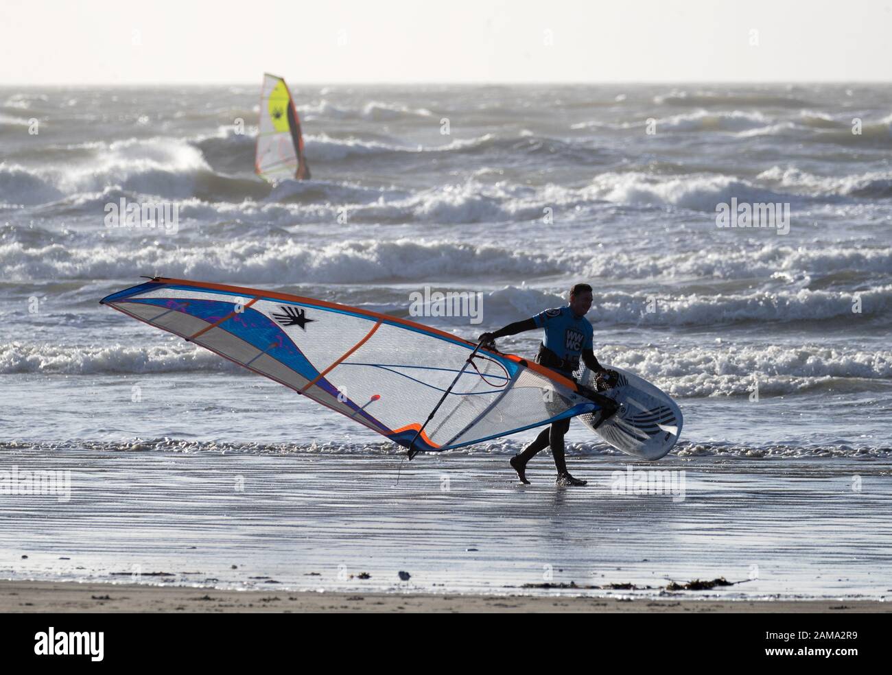 A windsurfer makes their way into the sea off of West Wittering beach ...