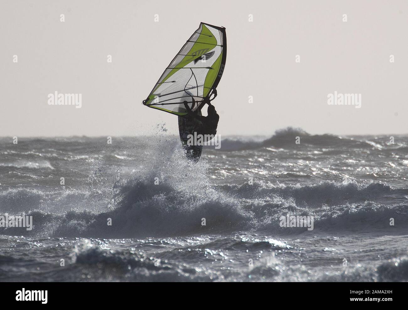 A windsurfer jumps in the air after hitting a wave in the sea off of ...