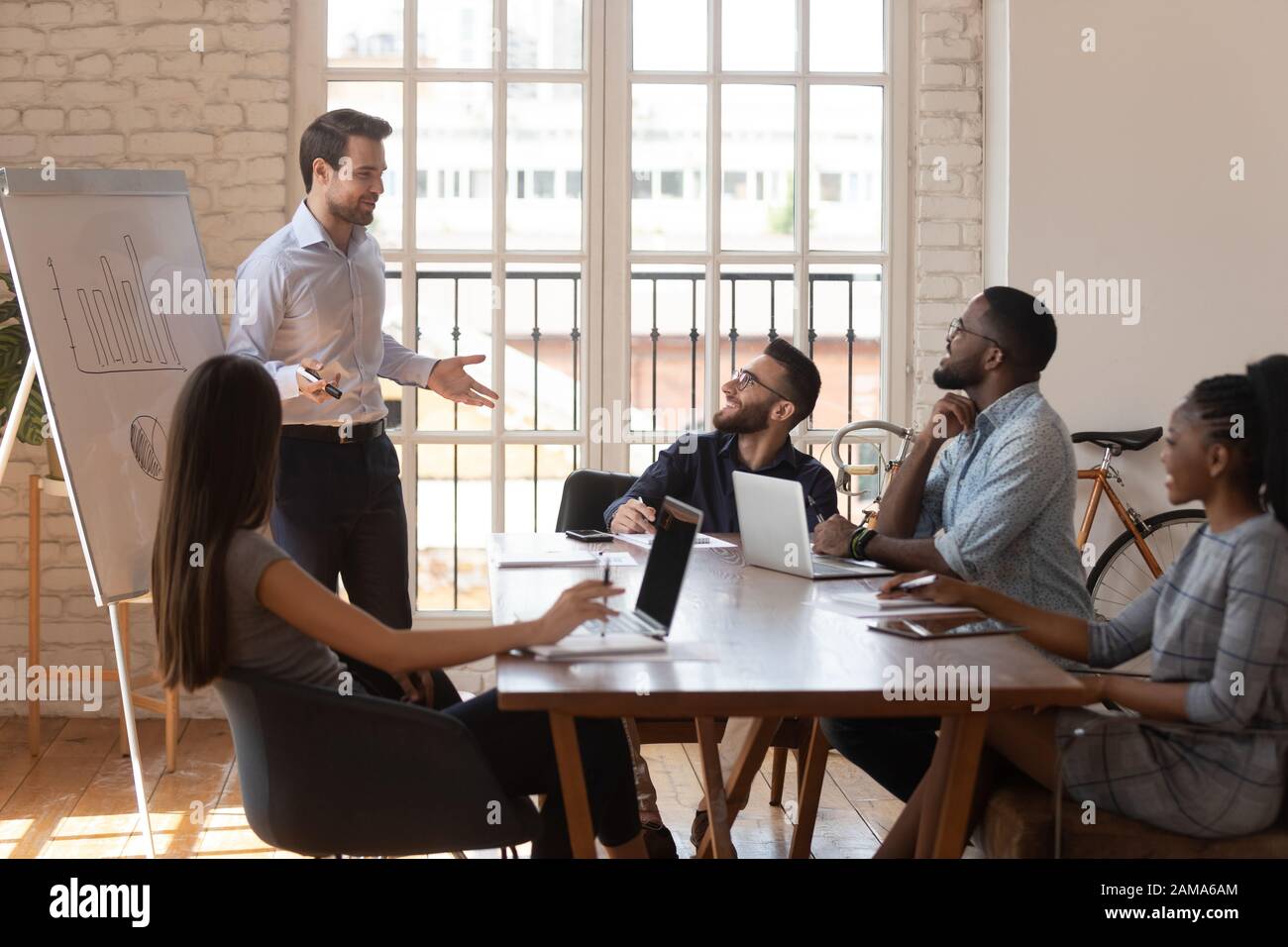 Smiling male presenter talk with excited multiethnic workers at ...