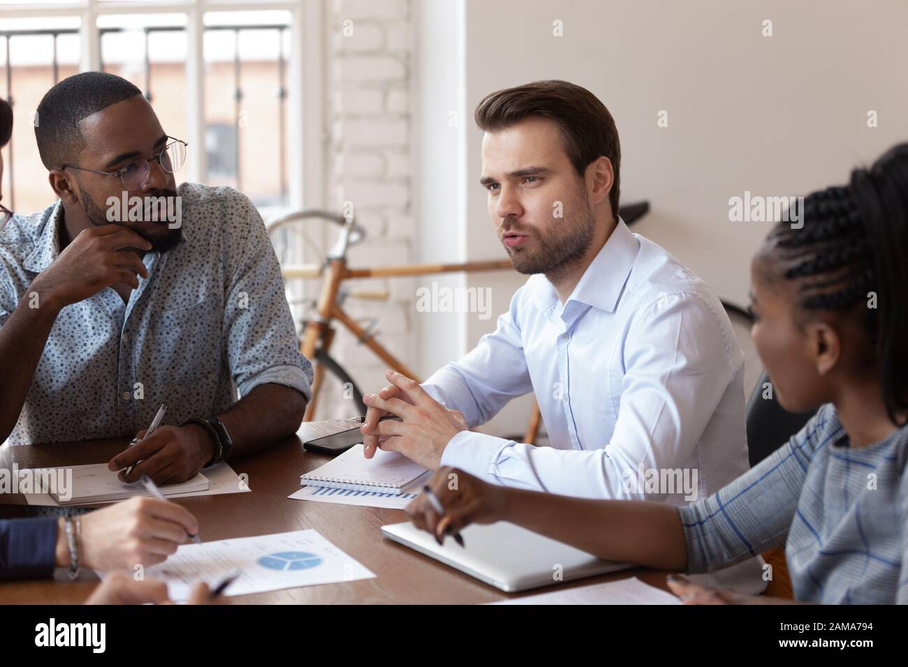 Focused multinational colleagues discuss ideas at meeting Stock Photo ...
