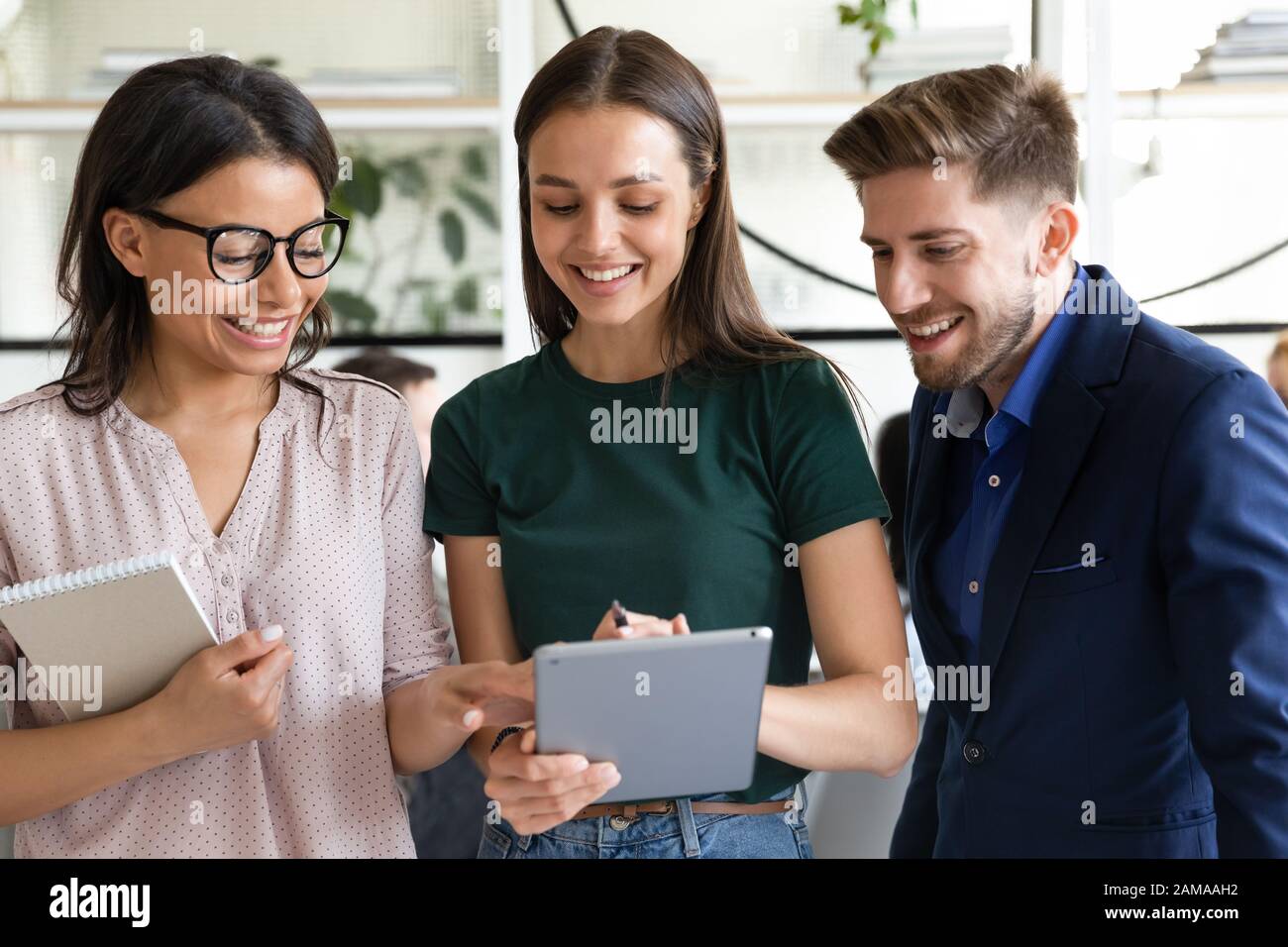 Three diverse colleagues discuss common task or project using tablet ...
