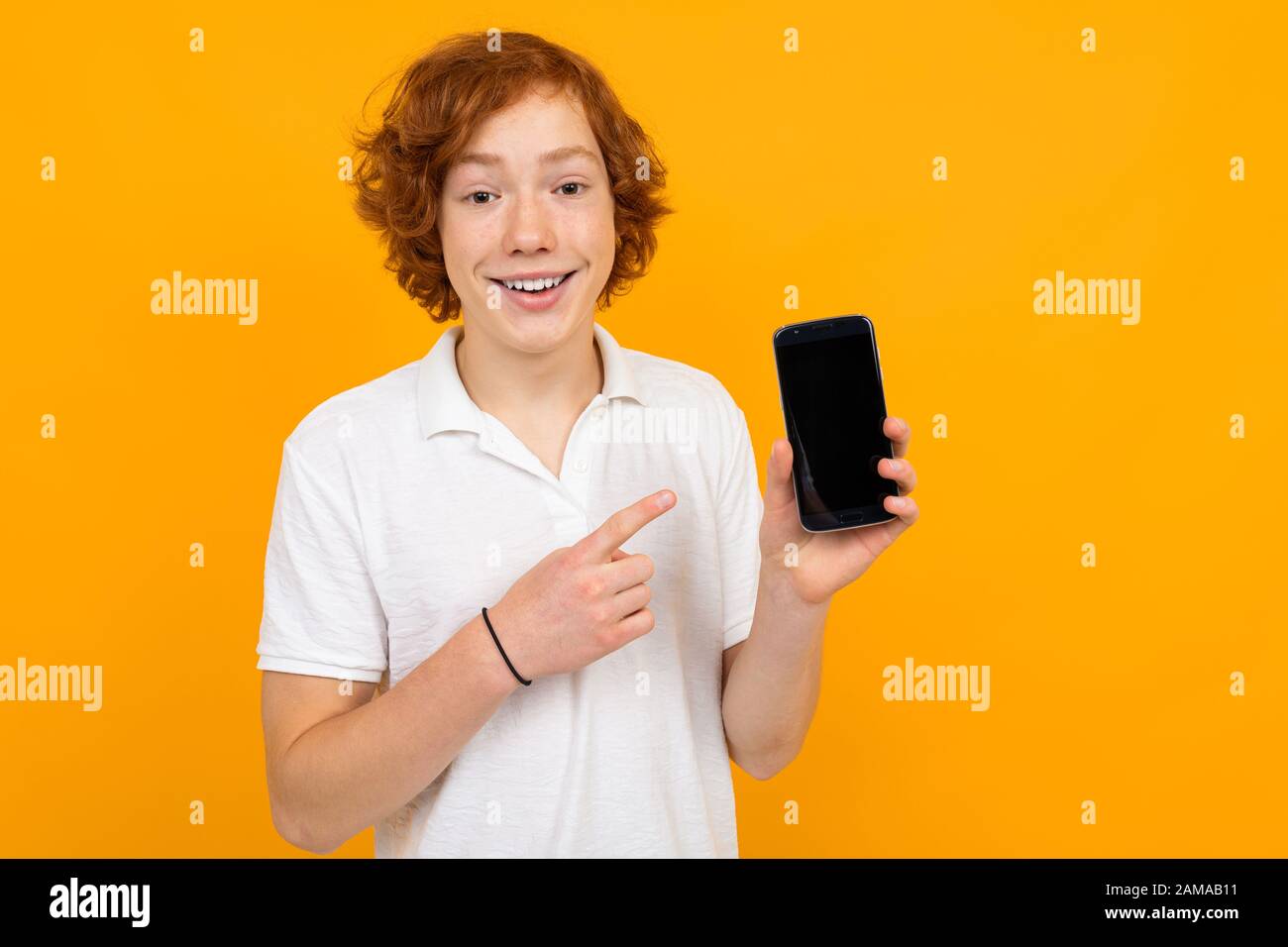 red-haired attractive handsome boy in a white T-shirt with a phone with ...