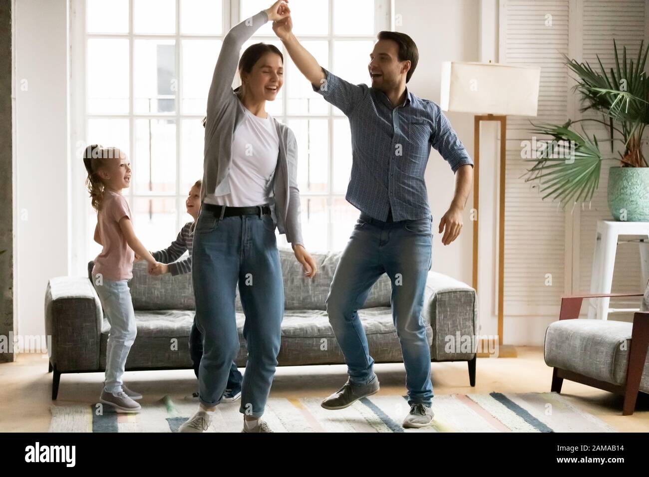 Happy young family with kids dancing together at home Stock Photo - Alamy