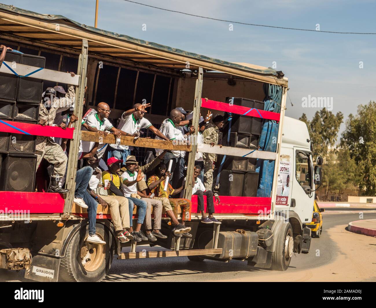 Dakar, Senegal - February 3, 2019: Africans sit on a truck, shout and ...