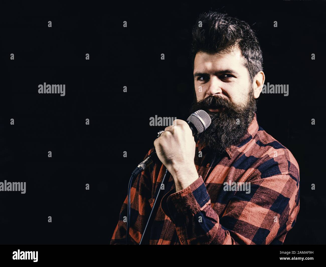 Musician with beard lighted by spotlight, copy space. Musician, singer ...