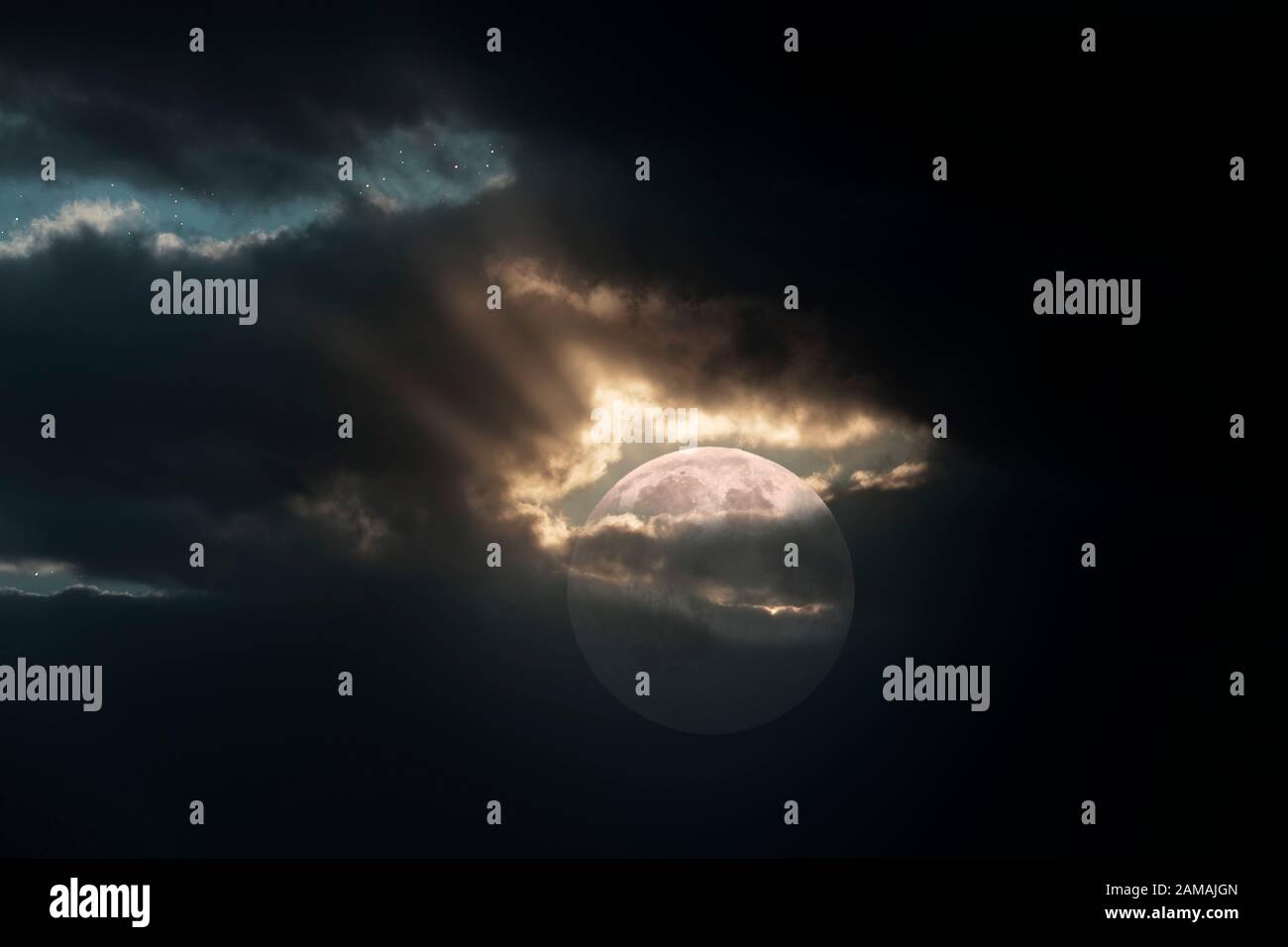 Full moon in an overcast night with light beams coming out of a hole in ...