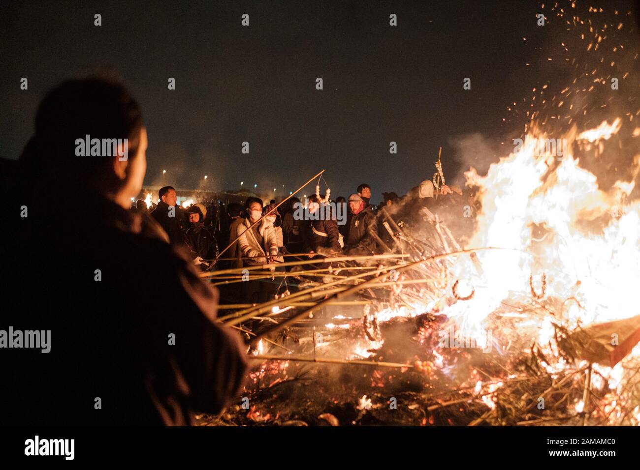 Oiso, Japan. 12th Jan 2020. People gather around large fire and warm ...