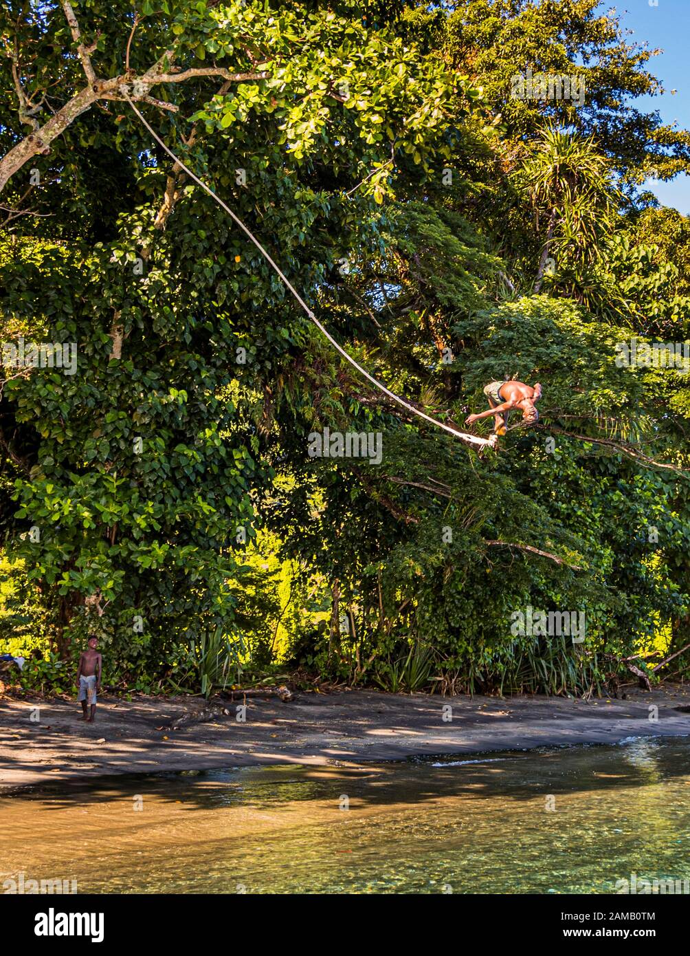 Tarzan exercise with jumping into shallow water on the beach in ...