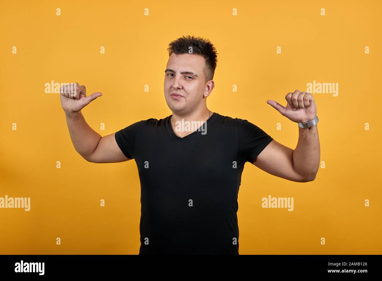 Charming young man pointing thumbs at himself, looking at camera Stock ...
