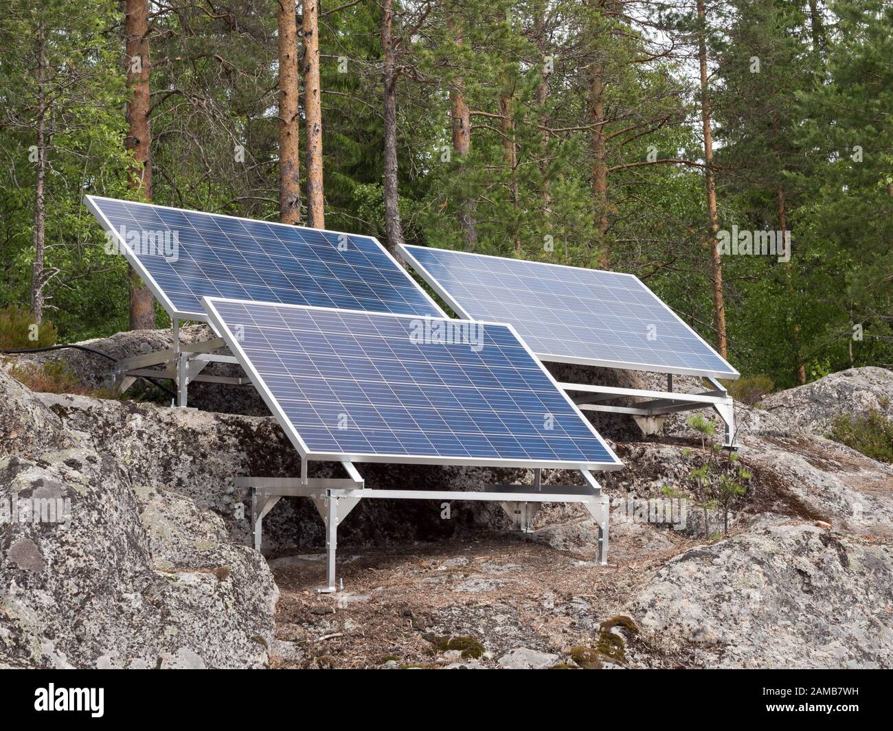Solar panels on rocky terrain by forest Stock Photo - Alamy
