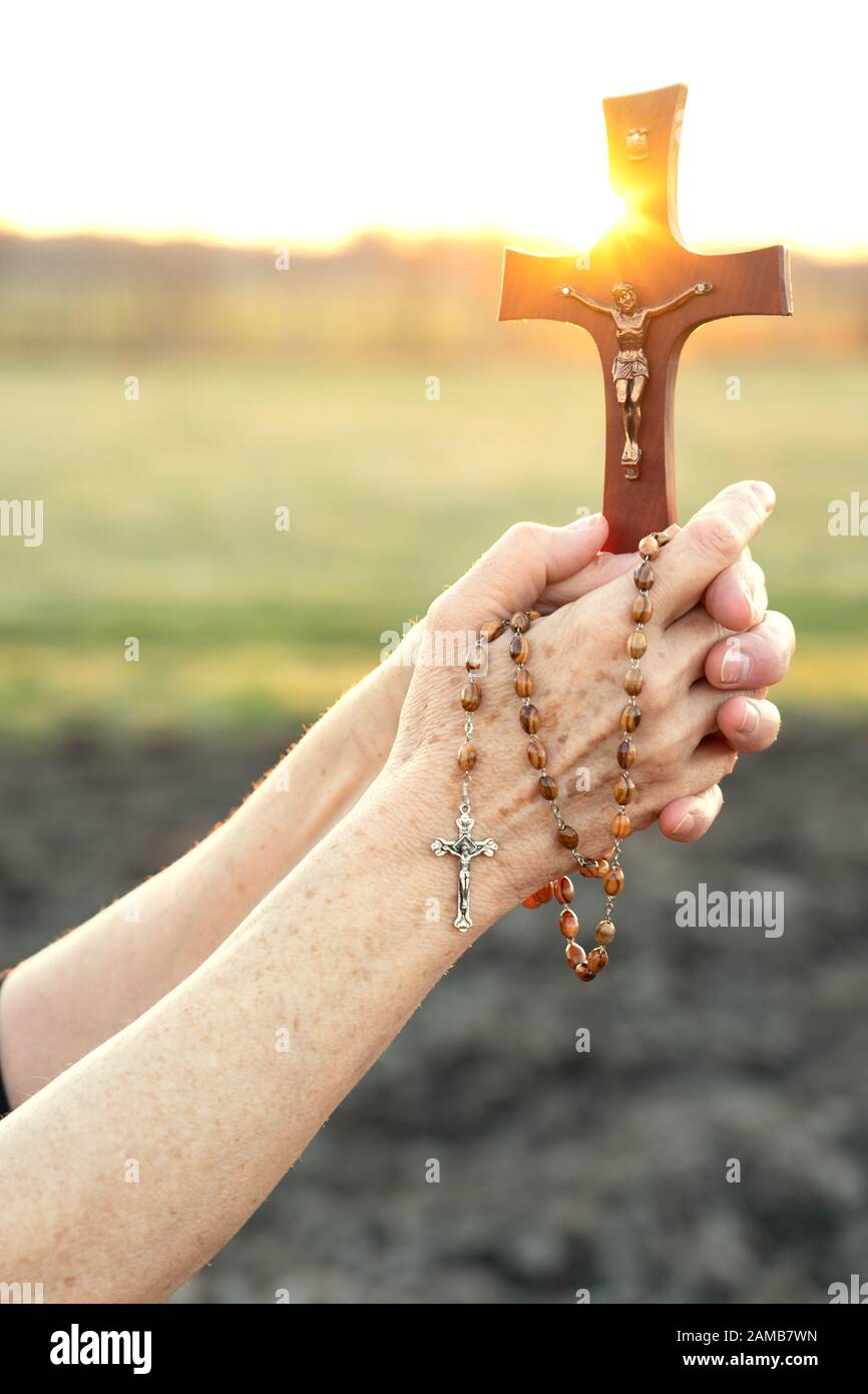 Woman praying outdoor with a crucifix at sunset Stock Photo - Alamy