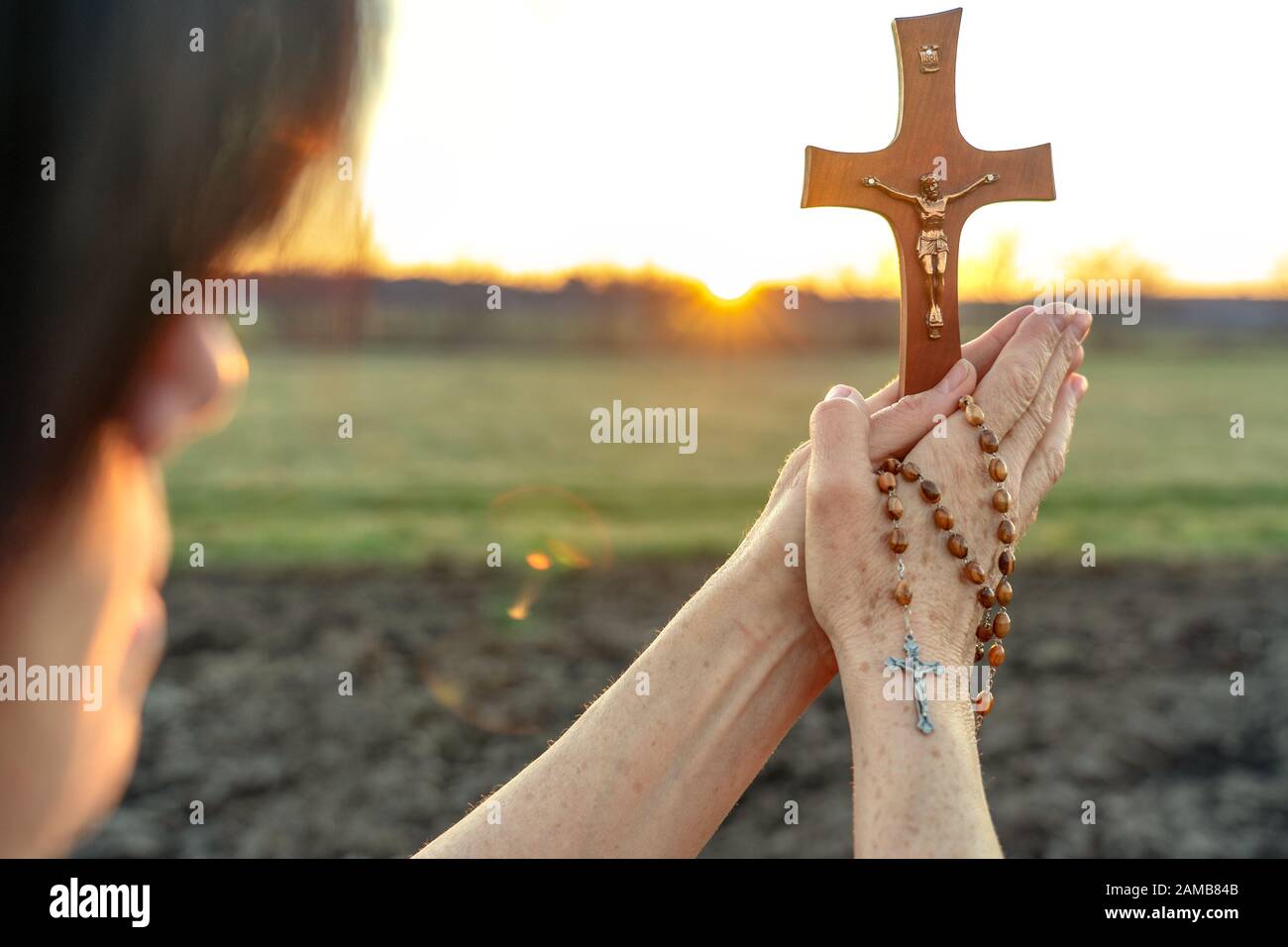 Woman praying outdoor with a crucifix at sunset Stock Photo - Alamy