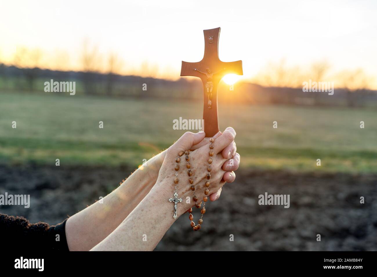 Woman praying outdoor with a crucifix at sunset Stock Photo - Alamy
