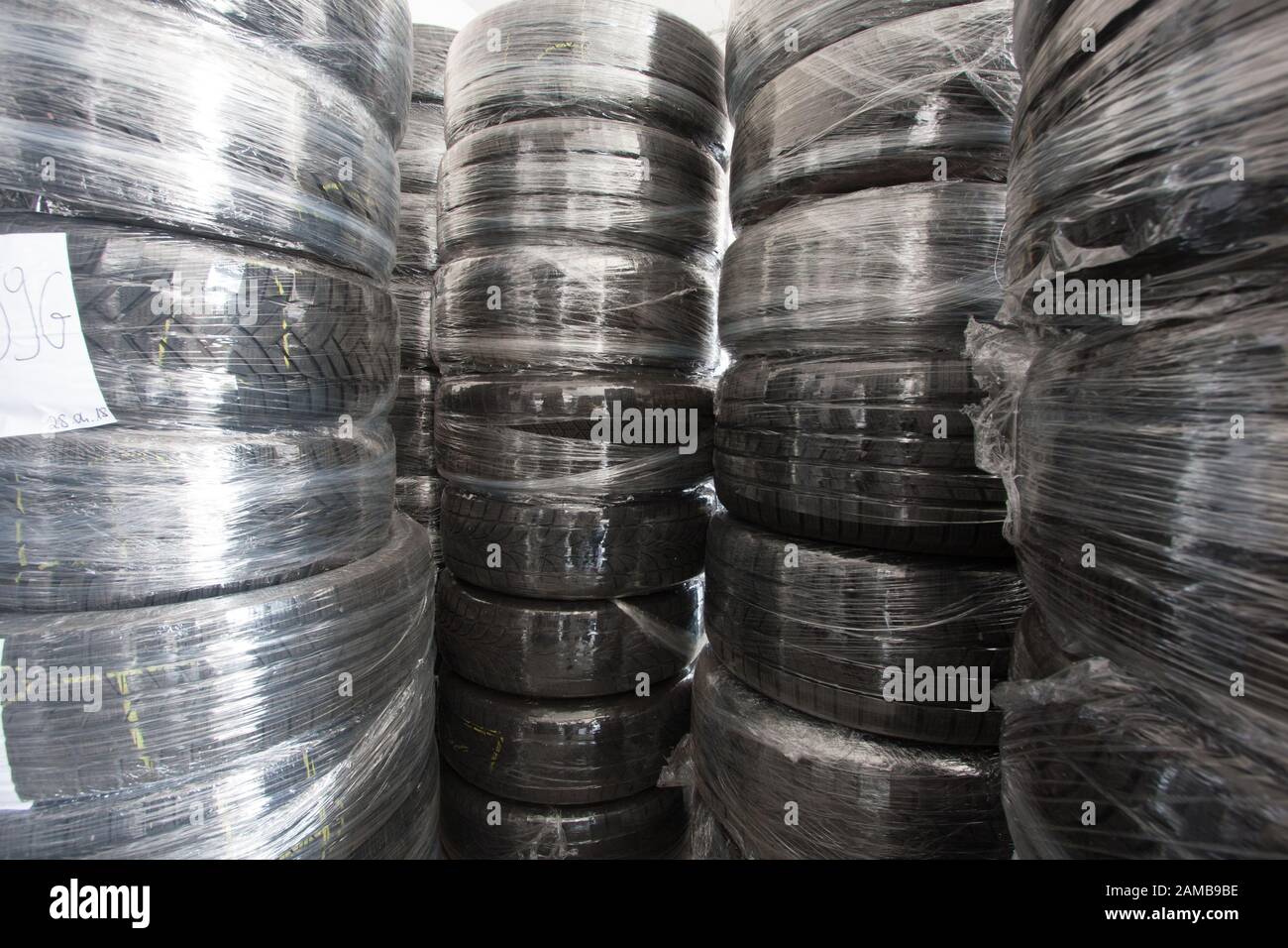 Stacks of used tires wrapped with foil are in stock. Black rubber tire ...