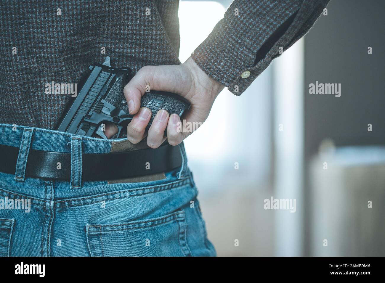 Undercover police agent is holding a black hidden weapon in his hand ...