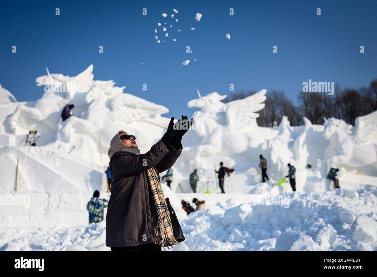 A tourist plays with snow in front of an ice sculpture during the 36th ...