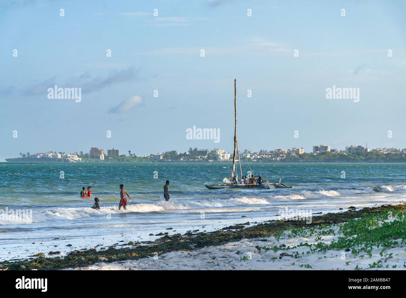 A traditional wooden dow sailing boat with passengers setting sail on ...