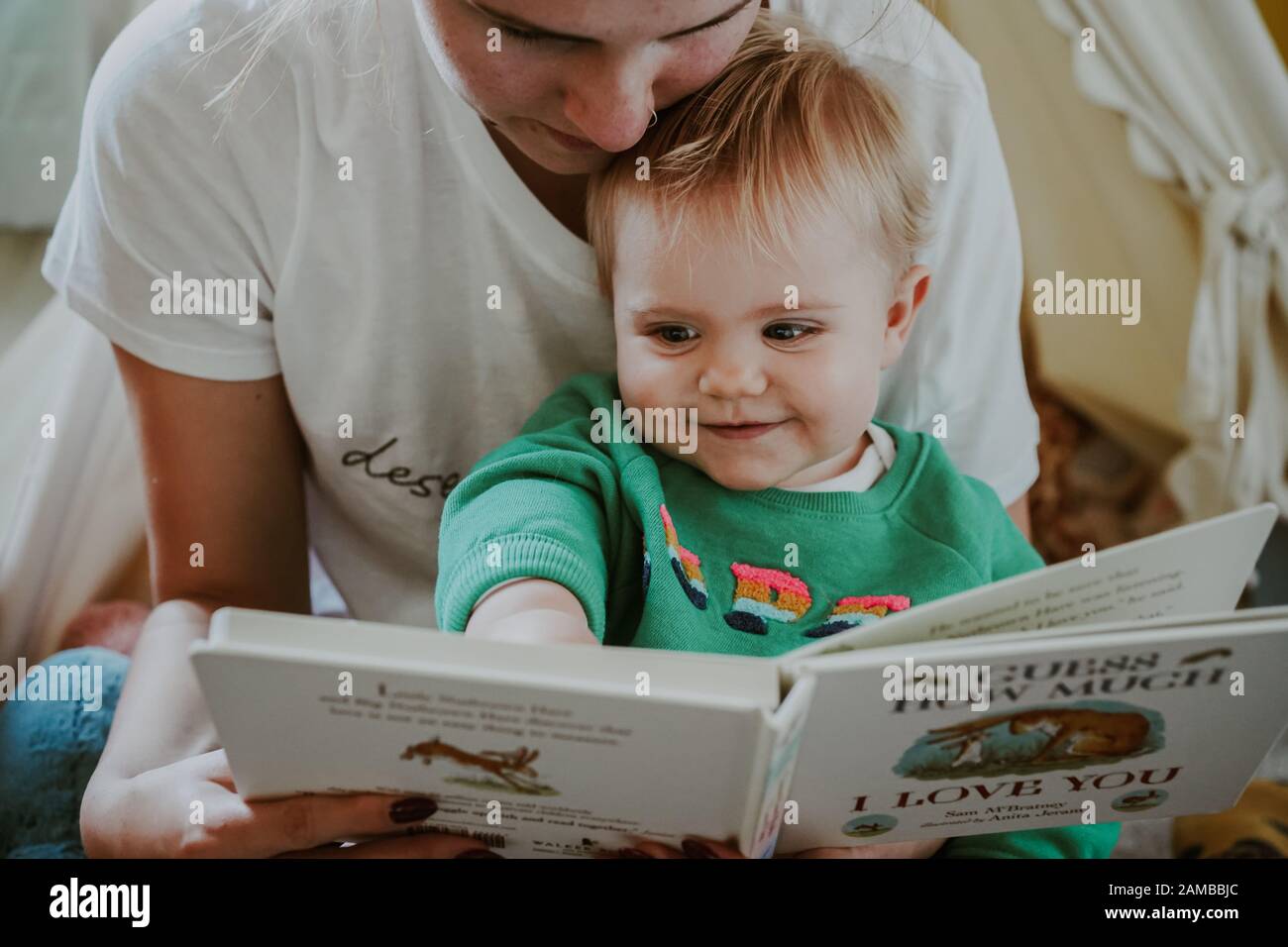 Young child reading with their mum Stock Photo - Alamy